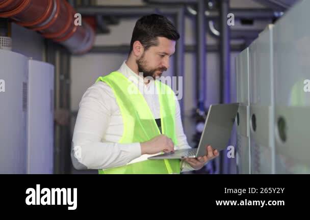 Professional engineer uses laptop to monitor and control heating system ...