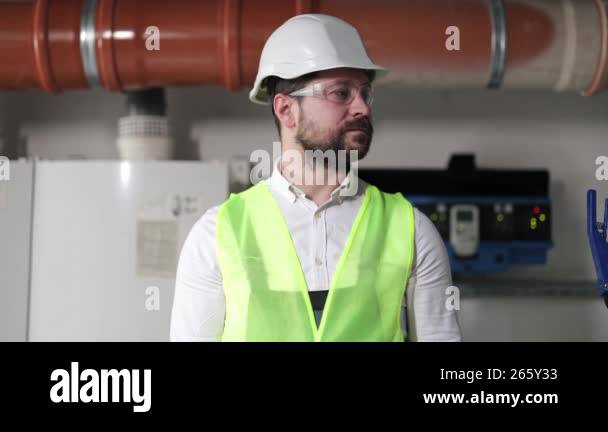 Confident bearded power generation plant worker with wrench, smiling at ...