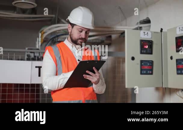 Caucasian electrical engineer in a white hard hat and orange vest ...