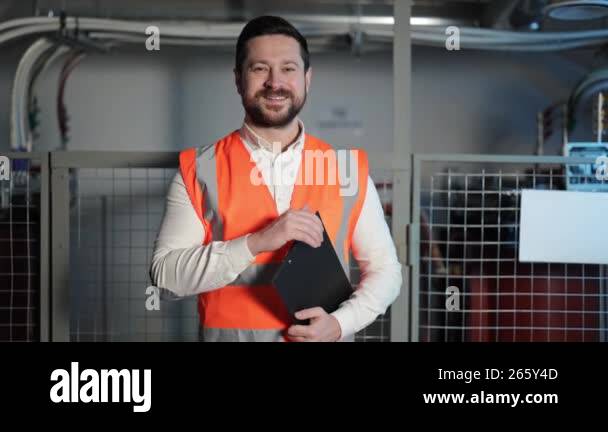 Confident electrical engineer smiles at camera while holding a ...
