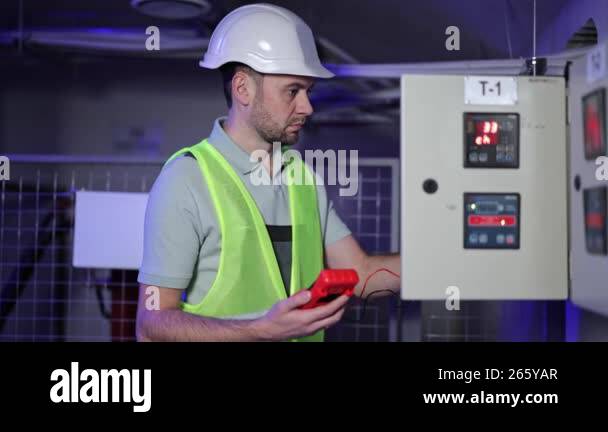 Serious engineer performs diagnostics of electrical control panel using ...