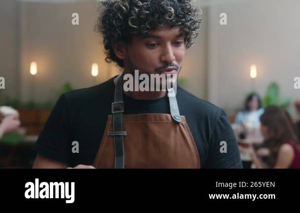 Arabian Indian Latino man chef waiter in apron serving customer in cafe ...