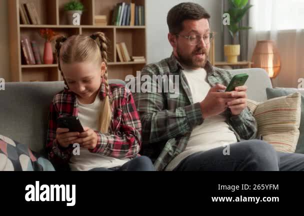 Caucasian Internet addicted male dad guy man kid daughter family using mobile phone smartphone ...