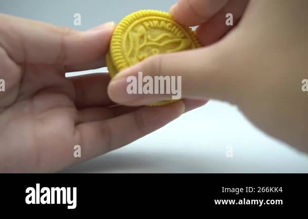 Hand opening a pokemon themed yellow oreo by rotating it against a ...