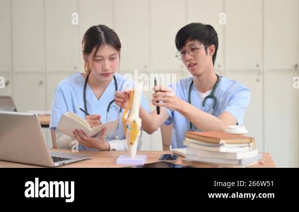Medical students in blue scrubs examining an anatomical model during a ...