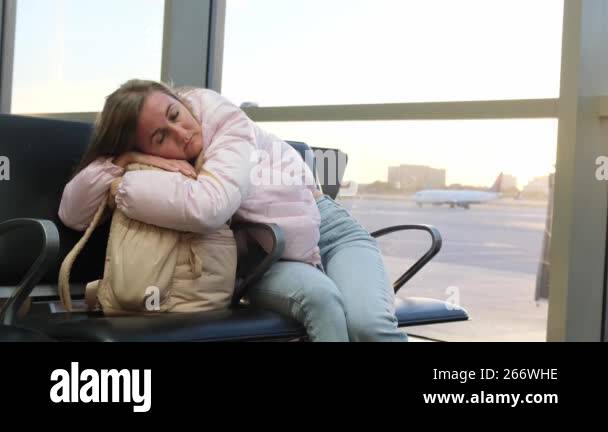 Tired caucasian woman sleeping in airport hall. Transit passenger waiting for flight during ...
