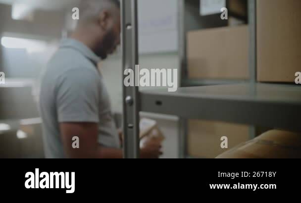 African American Warehouse Employee Scans Cardboard Box at Postal Terminal with Digital Screen ...