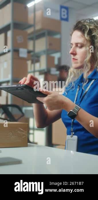 Female warehouse clerk scans parcels using tablet computer preparing ...
