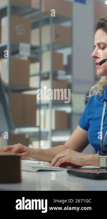Female customer support specialist in logistics in headset talks to client, uses computer, works ...