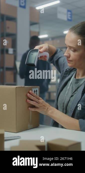 Female manager scans parcel using scanner, enters data on computer. Sorting center worker ...