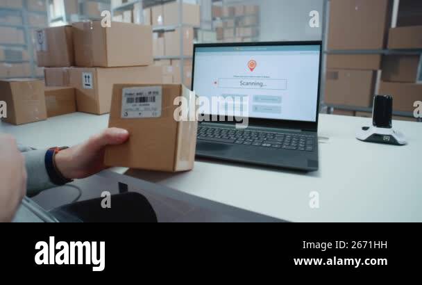 Logistics Specialist Scans Code on Cardboard Box with Barcode Scanner, Monitors Package ...