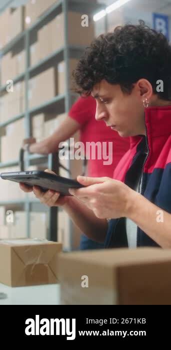 Male warehouse clerk scans parcels using tablet computer, works in ...