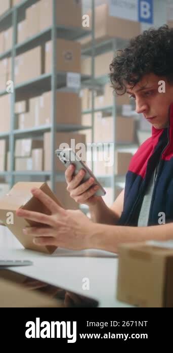 Logistics manager scans parcels using smartphone, works in warehouse of ...