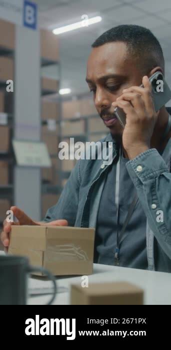 Warehouse of E-commerce store: African American logistics coordinator talks by phone, checks ...