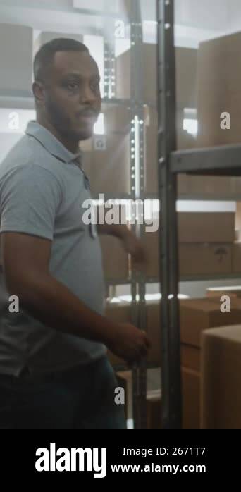 African American Warehouse Employee Loads Pallet Truck with Cardboard Boxes, Transports for ...