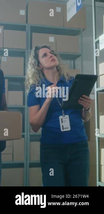 Female inventory manager walks with colleague, uses tablet computer ...