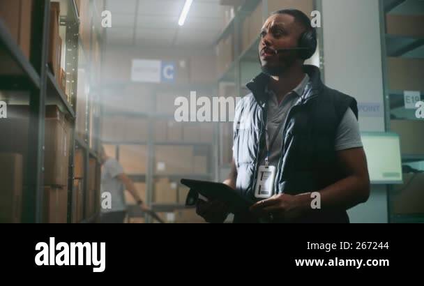 African American Logistics Coordinator in Headset Chats with Customer ...