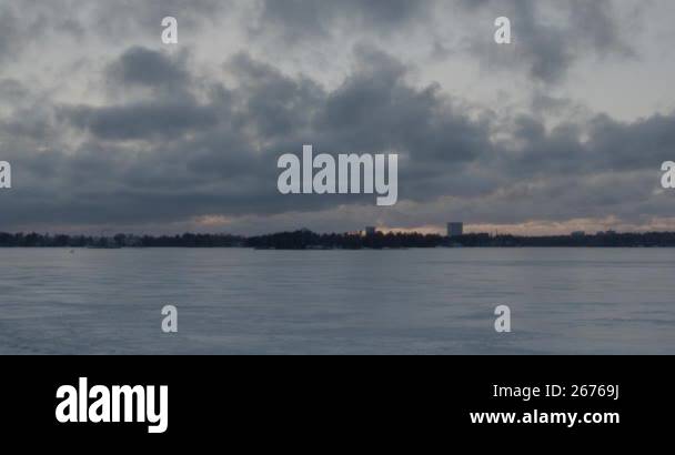 Sunset at Hietaniemi in winter with sea frozen and clouds moving across ...
