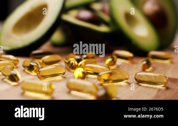 Close-up shot of avocado oil capsules with fresh avocado halves in the ...