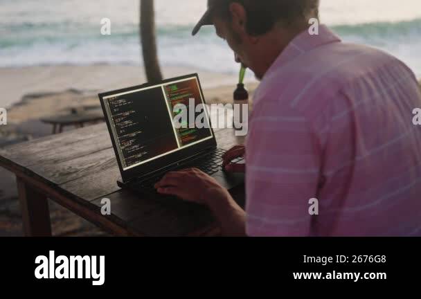 Male typing, edits code on laptop screen, enjoys tropical seaside view ...