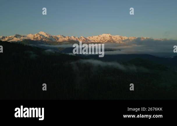 Aerial view above clouds of Svaneti mountains at dawn in Mestia. Snow ...