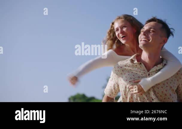 Happy husband carrying wife piggyback, running barefoot on tropical ...