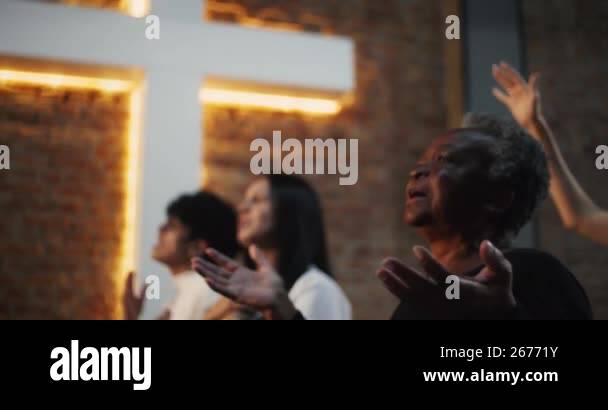 Diverse group worshiping in church with hands raised, expressing faith and devotion in unity ...