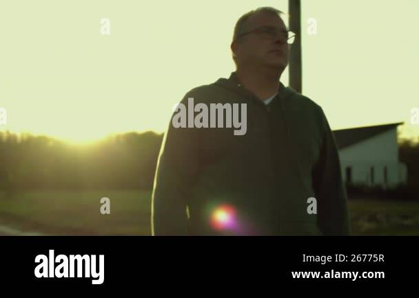 Man walking outdoors at sunset, peaceful rural environment, wearing ...