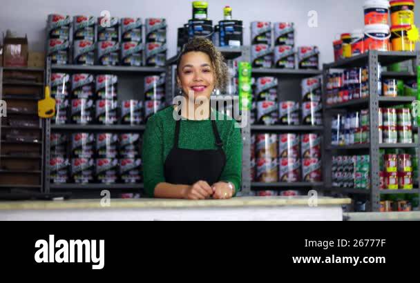 Confident employee smiling behind the counter of a hardware store, with ...