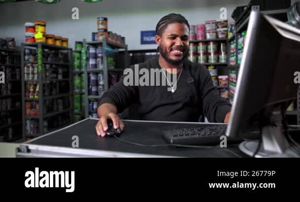 Man using computer at paint store counter, engaged in work, surrounded ...