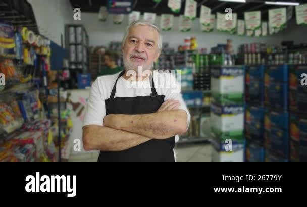 Older male store owner standing confidently with arms crossed in a ...