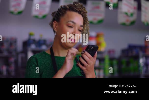 Shopkeeper browsing on smartphone in hardware store, managing tasks with focus and efficiency ...