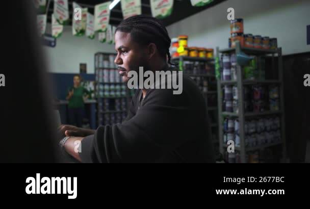 Thoughtful male paint store assistant leaning on counter, focused on ...