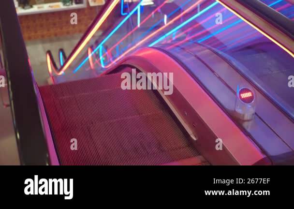 A beautifully colorful escalator showcases vibrant neon lights in an ...