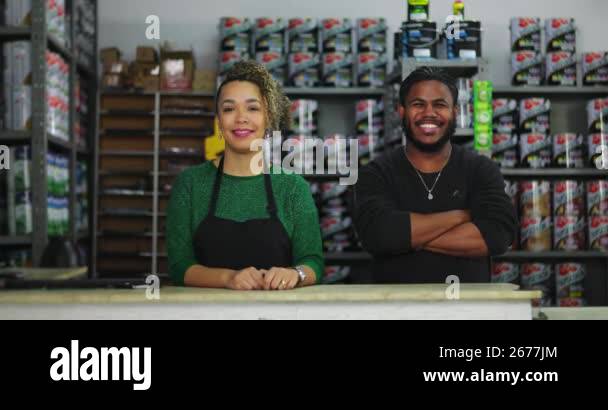 Smiling employees standing together behind the counter in a hardware ...