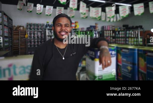 Smiling store clerk leaning on stacked paint cans in a hardware store ...