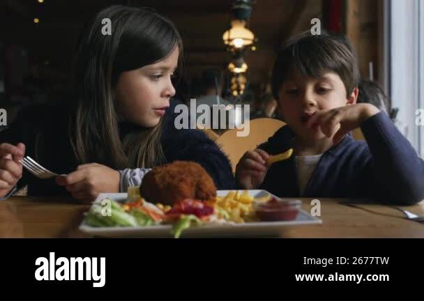 Joyful Mealtime - Siblings Enjoying Fries and Chicken at Restaurant ...