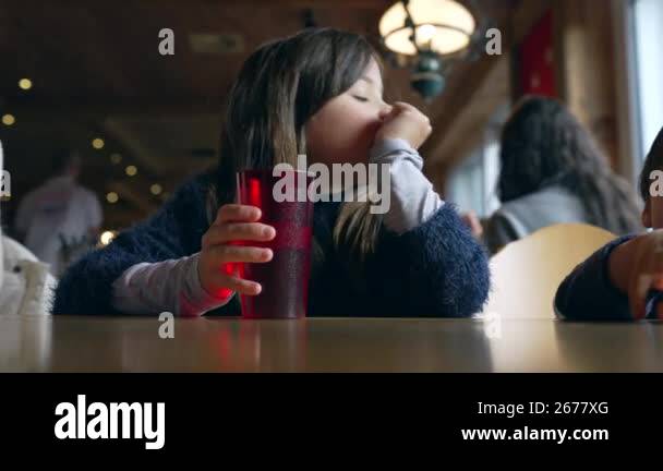 Small girl seated at restaurant waiting for food to arrive, drinks tap ...