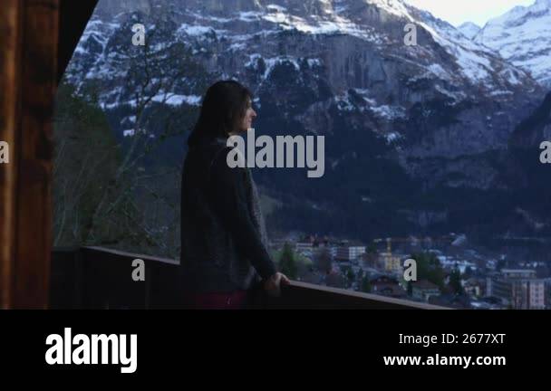 Vacationer on Swiss Alps Chalet Balcony in Winter, woman enjoys view of ...