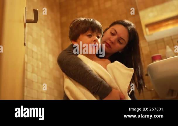 Mother kissing son on the cheek and drying body wrapped in towel after ...