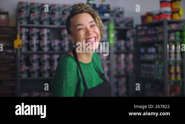 Smiling woman standing at counter in local small business hardware ...