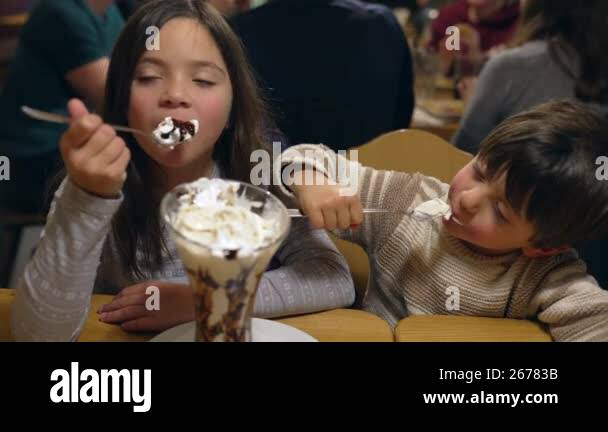 Kids eating whipped cream sundae at restaurant, brother and sister ...