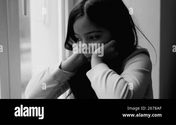 Preoccupied child in deep mental reflection by window staring with ...