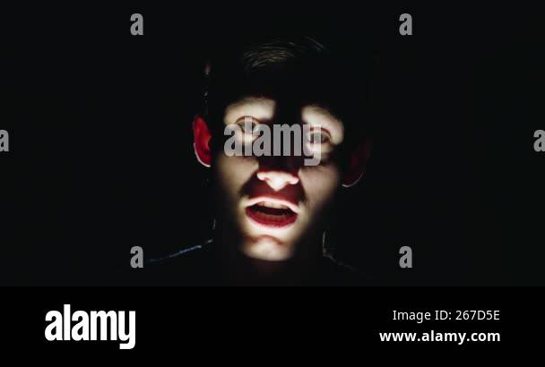 A young man contorts his face with creepy grimaces, flashes a ...