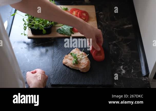 Young European man serving steak on a plate with vegetables and herbs ...
