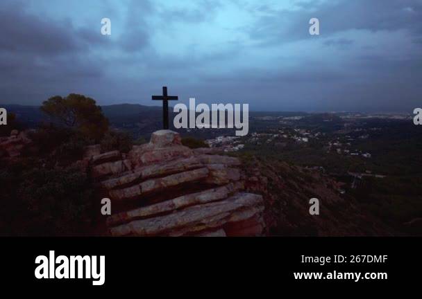 Dramatic scenery of a cross standing on a mountain peak with a valley ...