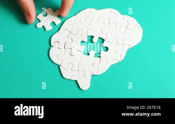 Placing the final puzzle piece into a complete brain shape on a teal ...
