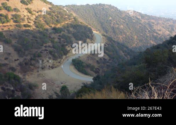 Individuals walking along a winding trail in Runyon Canyon Park ...