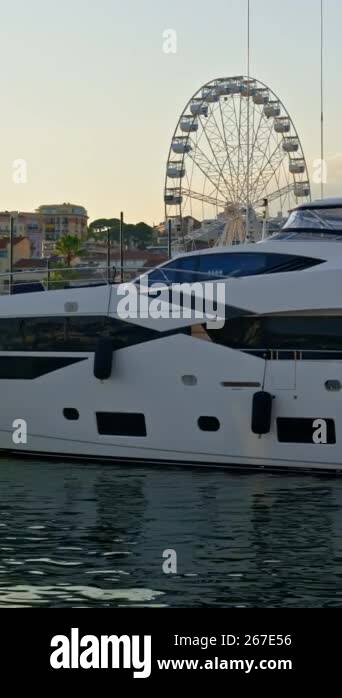 Boats docked in the Port de Cannes at sunset, with a ferris wheel ...