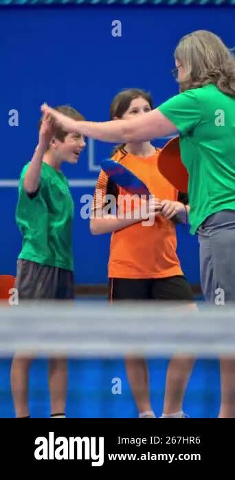 Two adults and two children high-fiving after playing pickleball on a ...
